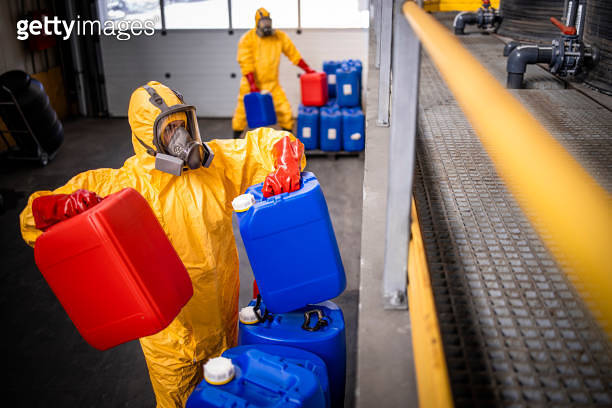 Chemical plant workers carrying plastic containers with chemicals or ...