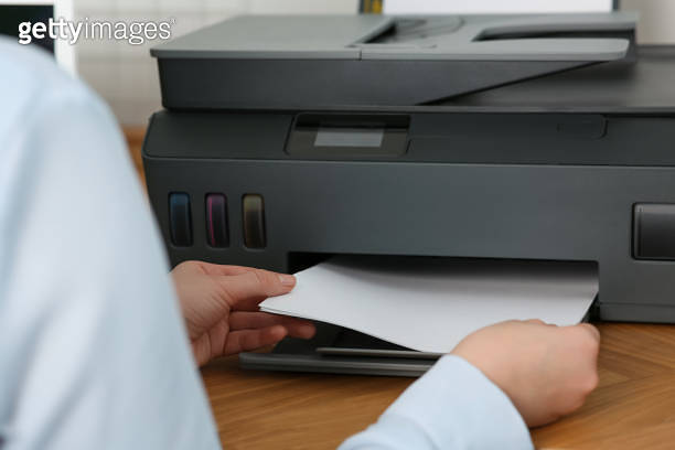 Woman loading paper into printer at wooden table indoors, closeup 이미지 ...