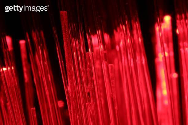 Optical fiber strands transmitting red light on black background, macro ...