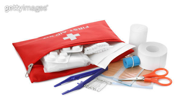 Red first aid kit with scissors, pins, cotton buds, pills, plastic ...