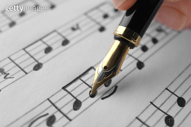 Woman writing musical notes with fountain pen on sheet of paper ...