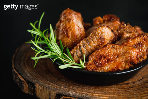 Semi-finished chicken wings on a dark background.Half-finished. Quick ...