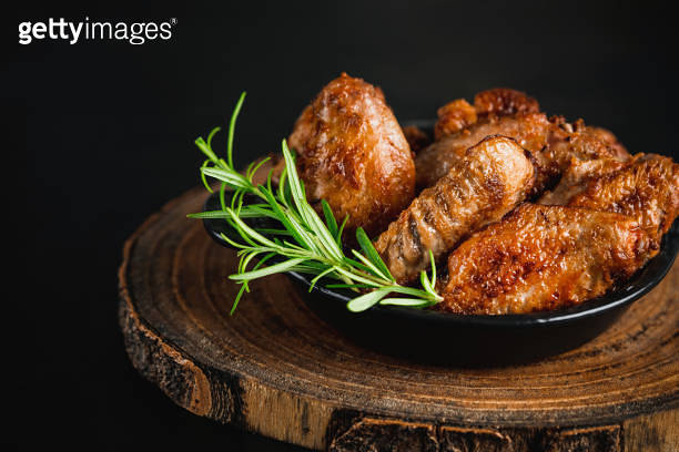 Semi-finished chicken wings on a dark background.Half-finished. Quick ...