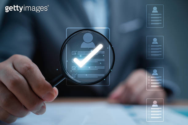 Businessman holding magnifier glass to focus on resume with tick mark ...