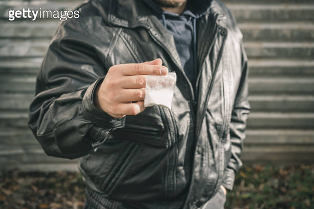 Dangerous drug dealer sells hard drugs, holding in the hand transparent ...