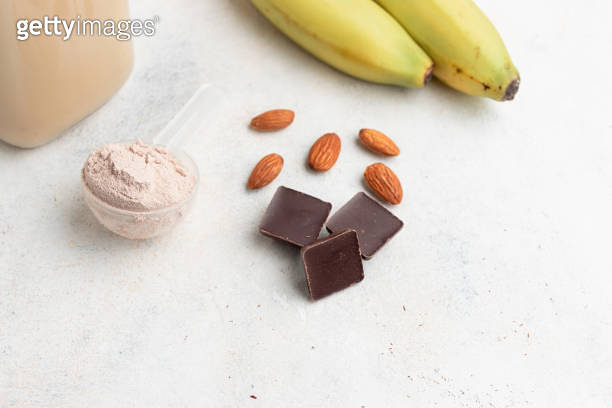 Chocolate whey protein powder in measuring spoon, glass jar of protein ...