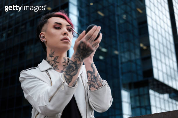 Portrait of non-binary male doing himself makeup outdoors. 이미지 ...