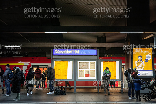 People waiting for trains in front sign indicating Dusseldorf Hbf, or ...