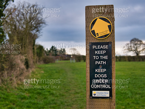 A way marker indicates a public footpath ahead, fixed to a wooden post ...