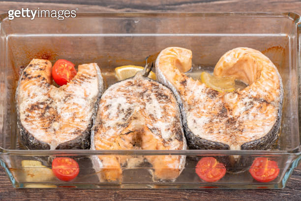 Delicious portioned steaks in a glass baking dish with lemon and ...