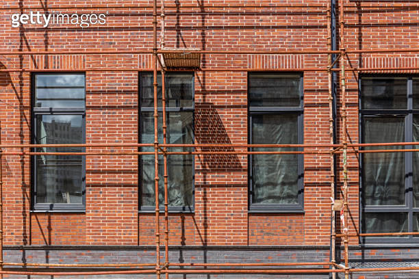 red brick wall with scaffolding during renovation works. refurbishment ...
