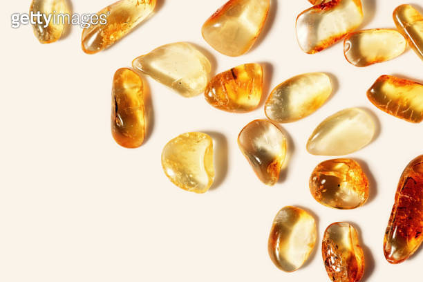 Amber stones at sunlight on beige background, minimal style frame with ...