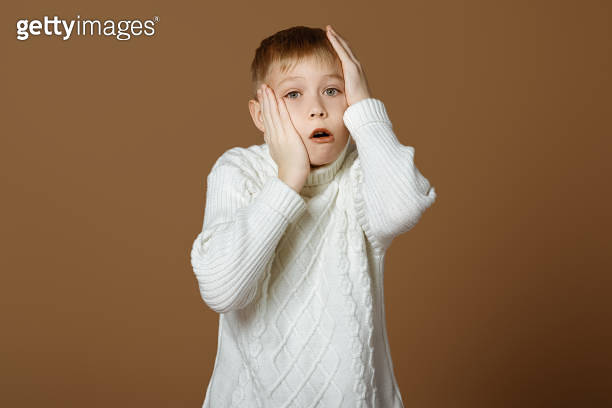 Scared, shocked, worried teen boy, grabs his head with his hands ...
