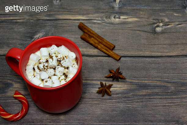 red mug with marshmallows, cinnamon sticks and badian on wooden ...