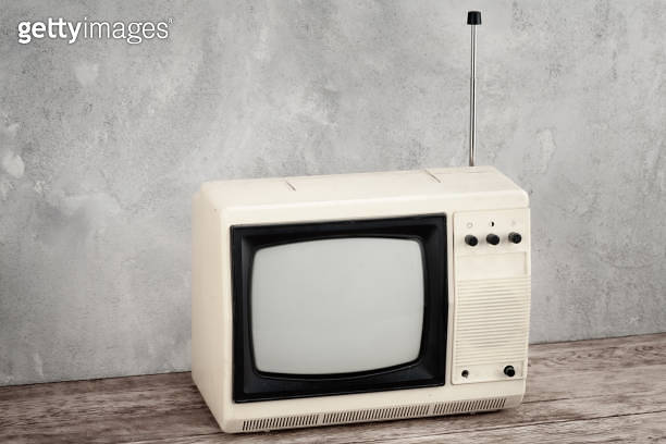 Vintage analog small TV set stand on wooden floor front grey concrete ...