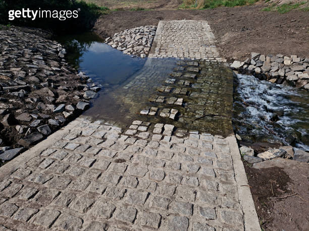 The dirt road leads across a stream that crosses river and continues ...