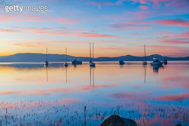 Beautiful sunrise waterscape with high cloud, reflections and boats 이미지 ...