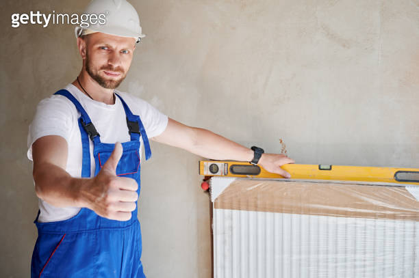 Man leveling heating radiator with level ruler and giving thumbs up ...