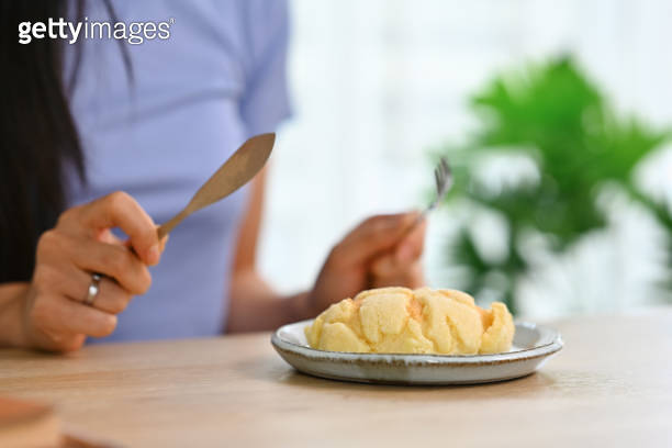 Pretty young asian woman eating pastry with great pleasure while ...