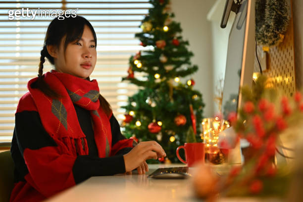 Young woman in sweater looking at computer monitor while working in ...