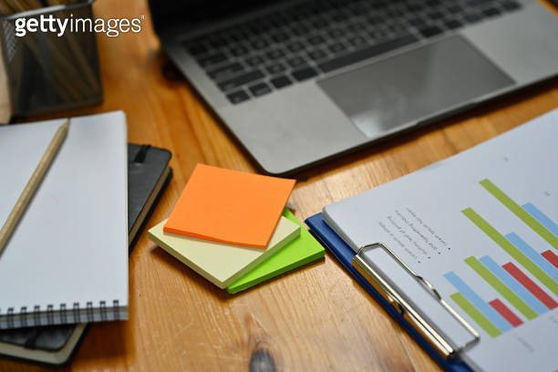 Colorful sticky notes, financial document, notebook and laptop computer ...