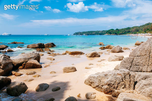 Tropical beach with clear blue water and large rocks on the shore in ...