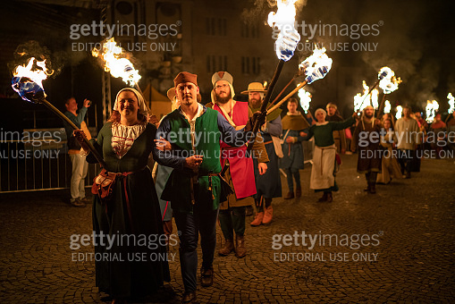 People dressed in medieval dresses and armored knights with a flaming ...