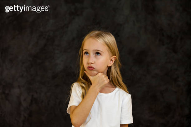 Portrait of puzzled girl child model in white t-shirt expression ...