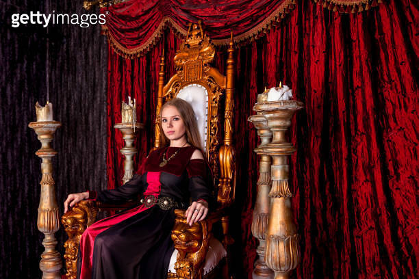Lovely lady in an old style on antique throne fortress, looking at ...