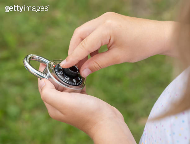Child unlocking a simple closed coded lock, holding a code padlock in ...