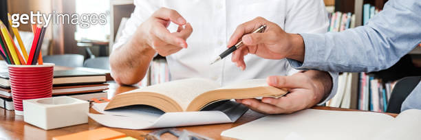 University students studying and reading together in library research ...