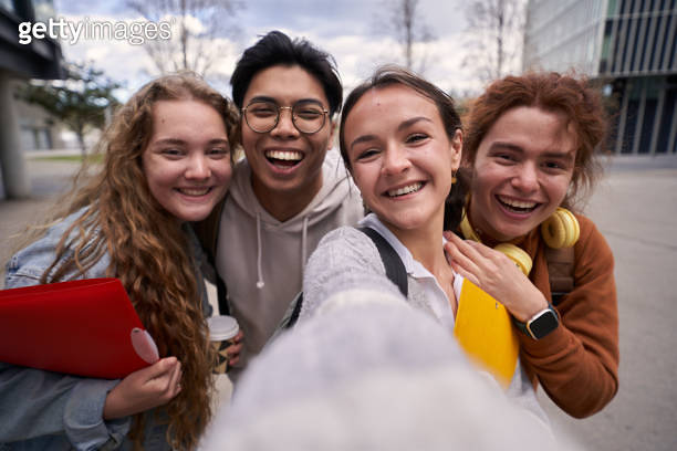 Group of four students having fun by taking a selfie outdoors. The ...
