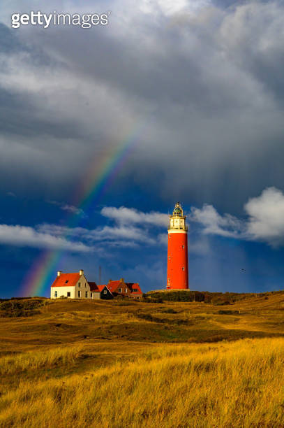 Texel lighthouse in the dunes with a rainbow during a stormy autumn ...