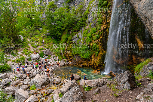 Tourists enjoying the Grunas waterfall in Theth National Park, Albania ...