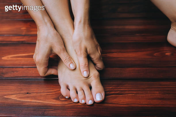 A two woman's hand massages her own foot. The concept of leg fatigue ...