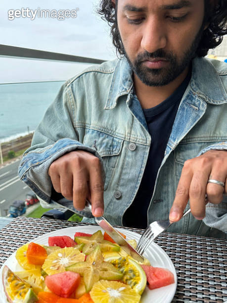 Close-up image of Indian man cutting up fresh, tropical fruit salad ...