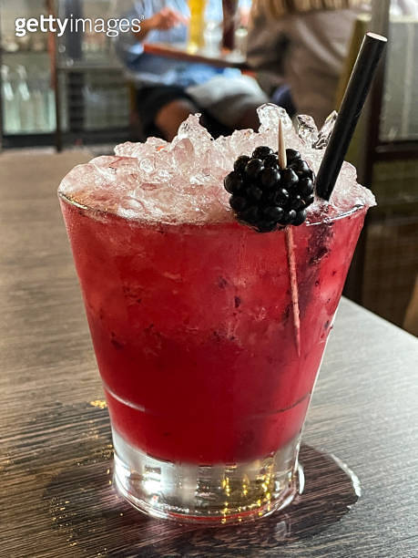 Close-up image of bar setting, drinking glass of bramble cocktail drink ...