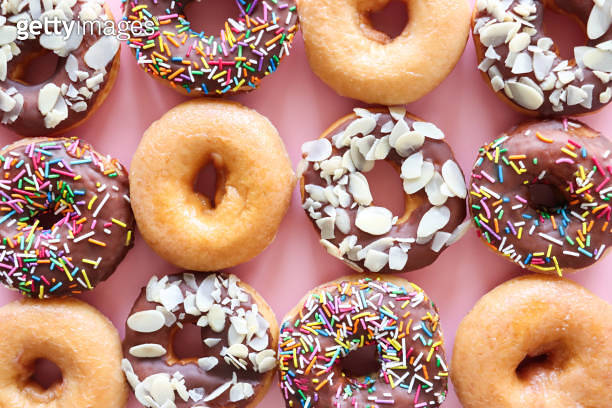 Full frame image of rows of alternating mixed, glazed ring doughnuts ...