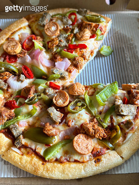 Full frame image of sliced, meat feast pizza in cardboard takeaway ...