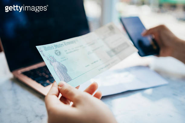 A woman is holding a tax refund check in her hand in the living room of ...