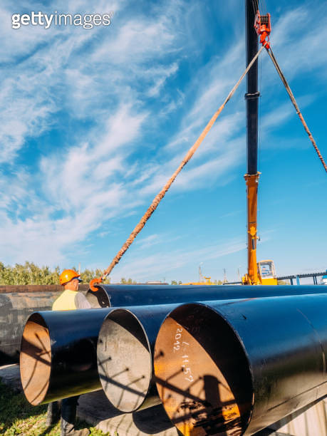 Slinger unloads large gasification pipes on summer day. Storage of ...