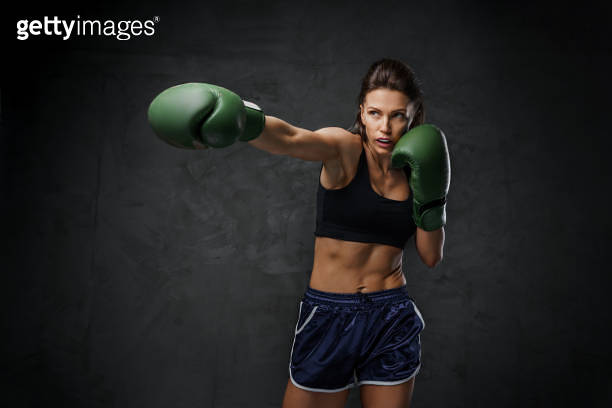 Female fighter in sports bra and boxing gloves showcases striking ...