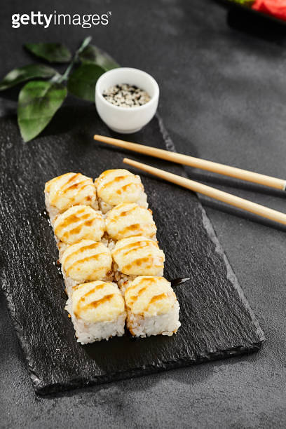 Baked Maki sushi on dark slate. Hot cheese maki with unagi sauce. Sushi ...