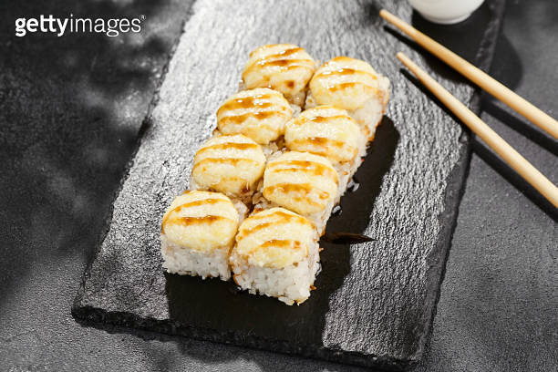 Baked Maki sushi on dark slate. Hot cheese maki with unagi sauce. Sushi ...