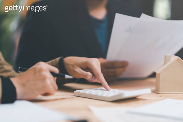 Real estate agent calculates numbers on financial documents with ...