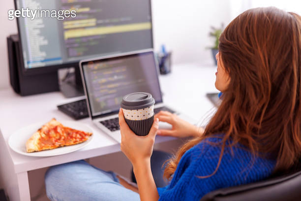 Female programmer drinking coffee and eating pizza while working ... Female programmer drinking coffee and eating pizza while working ...