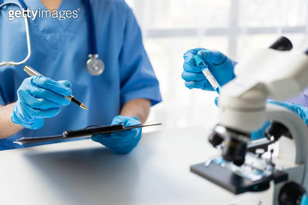 Two scientists working together analyzing chemicals in a flask and ...