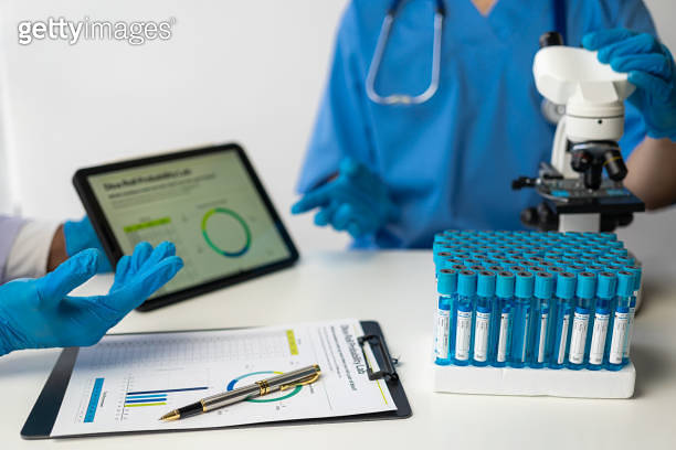 Two scientists working together analyzing chemicals in a flask and ...