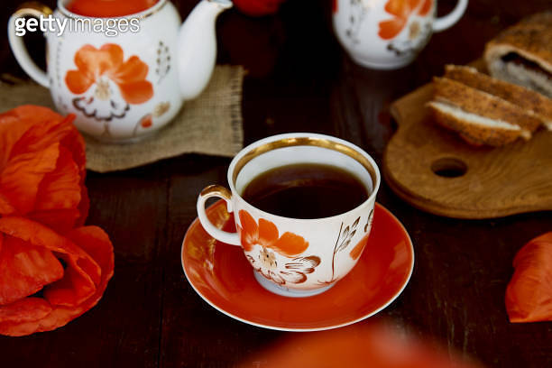 Traditional poppy seed buns, cup of black tea and milk among poppies ...