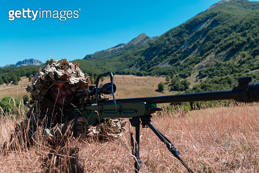 Army soldier holding sniper rifle with scope and aiming in forest. War ...